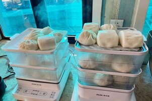 Vários recipientes com alimentos dentro, colocados sobre uma bancada perto de uma janela.