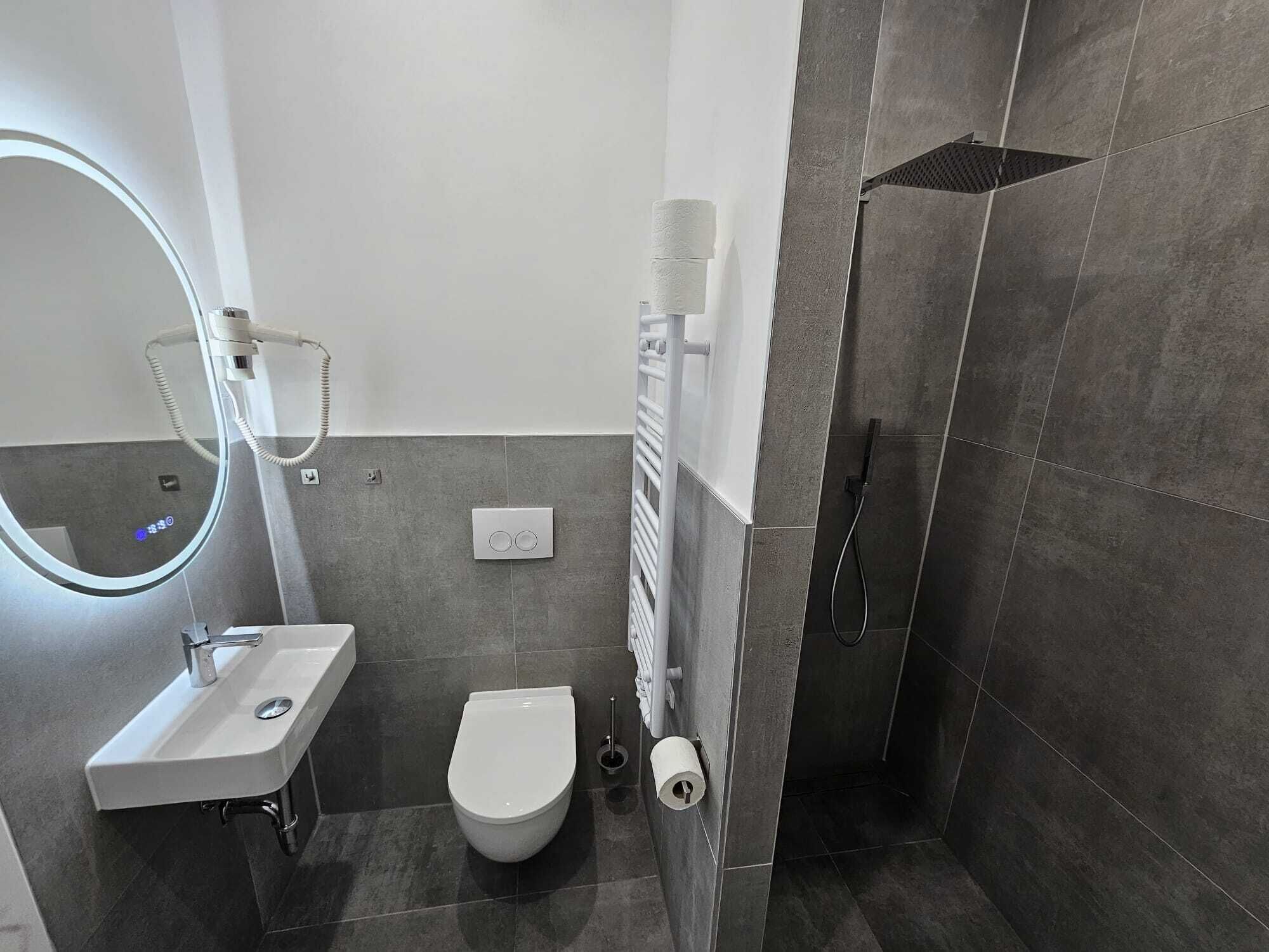 Uma casa de banho moderna com sanita, lavatório e chuveiro.