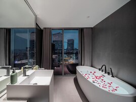 Uma casa de banho moderna com uma banheira grande, zona de duche separada e toucador com espelho.