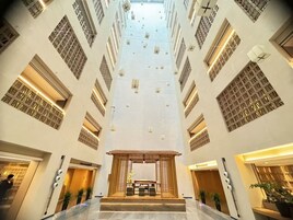 Interior moderno de hotel com um átrio central, vários andares e uma área de recepção na base.