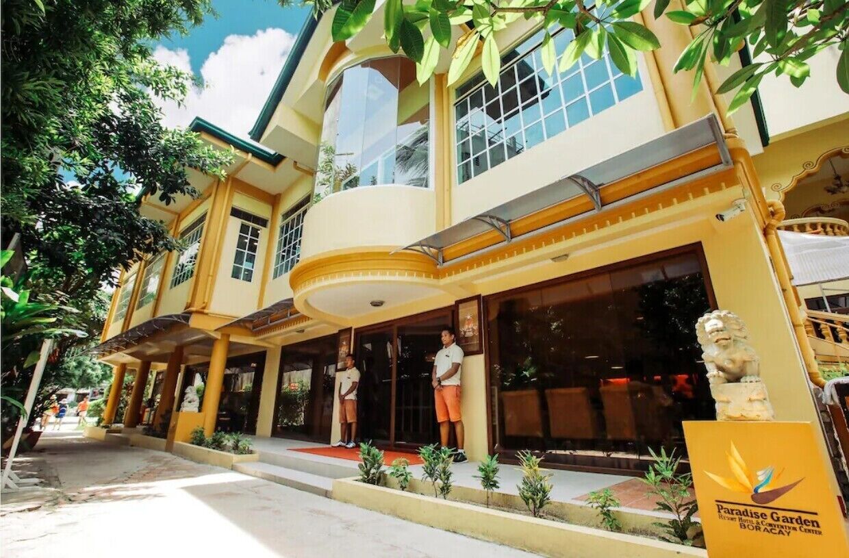 Um hotel com entrada curva, janelas amplas e uma estátua em frente.