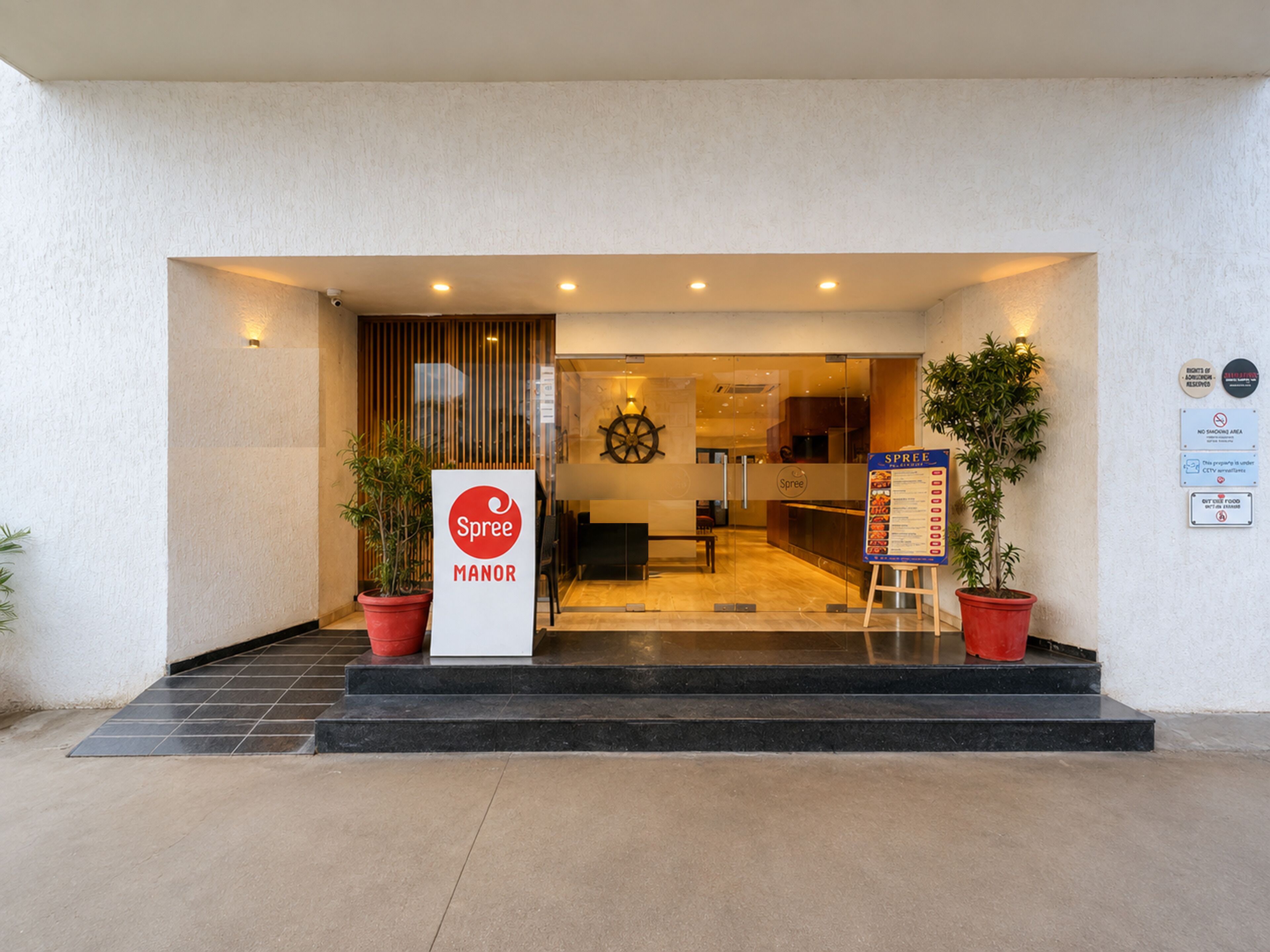 A entrada do Spree Manor, com uma mesa de recepção, um quadro de menu e plantas em vasos.