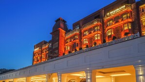 Um hotel com vários andares, uma entrada imponente, varandas e fachada bem iluminada.