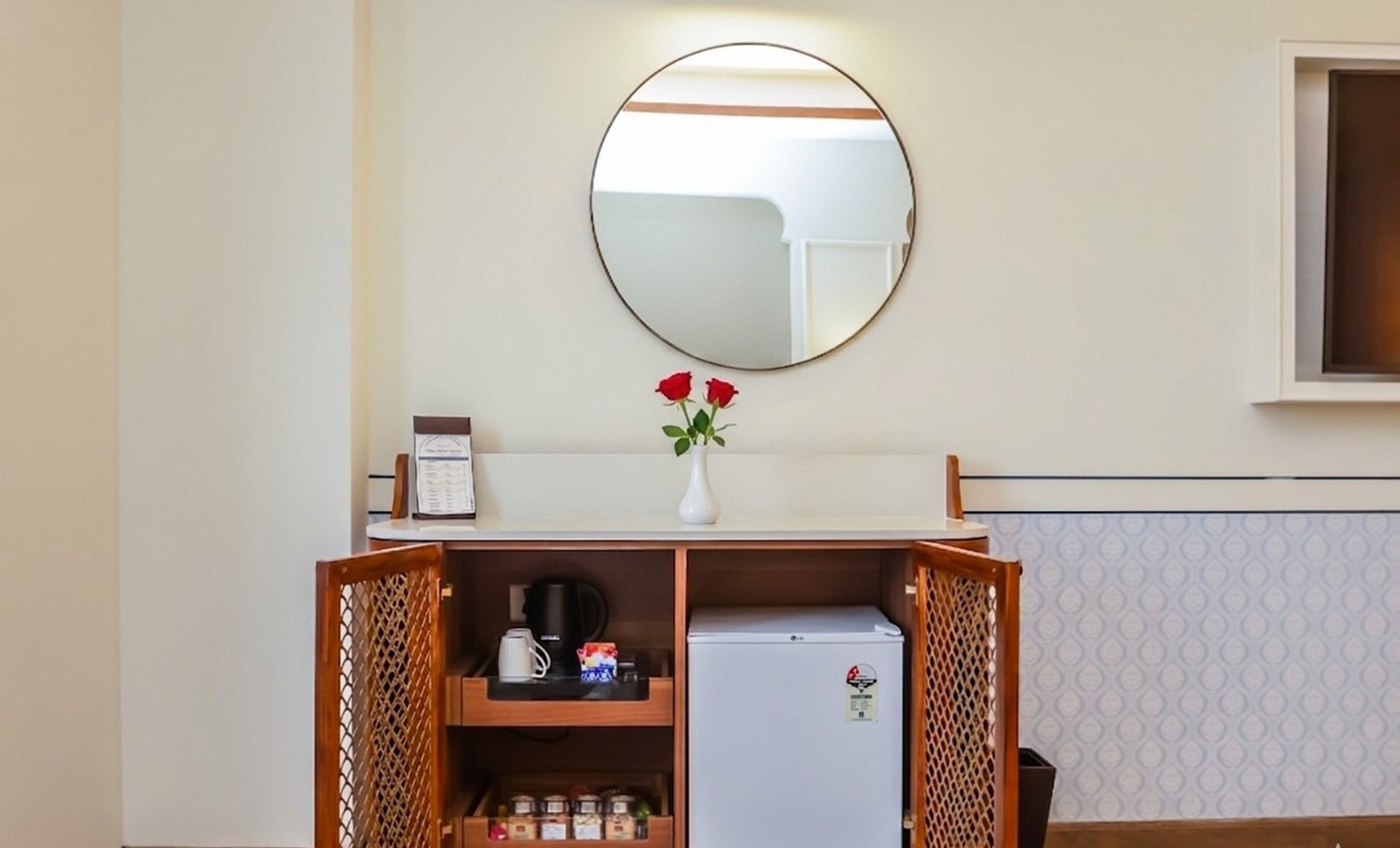 Uma cozinha compacta com cafeteira, um frigorífico pequeno e um vaso de flores na bancada.