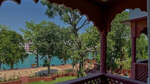 Varanda com vista para uma piscina e árvores, uma pérgula e uma cerca de madeira.