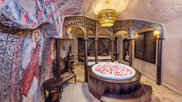 Um quarto de spa com hidromassagem, mobiliário de madeira e elaborados entalhes nas paredes.