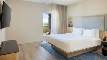 Quarto de hotel com cama grande, televisão, escrivaninha e vista para o exterior.
