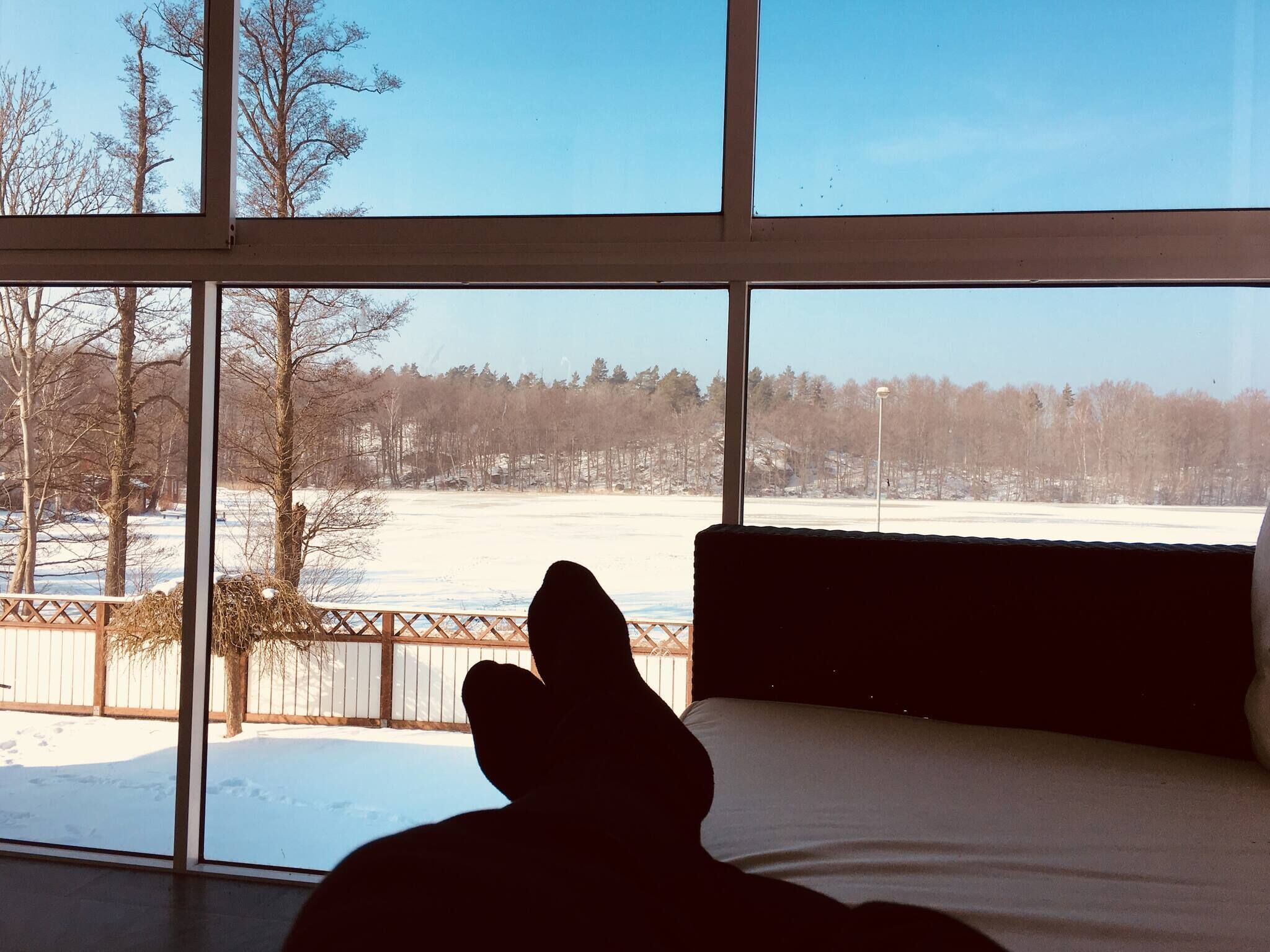 Quarto com grandes janelas com vista para uma paisagem nevada, com árvores e uma cerca.