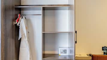 Um closet espaçoso com cabideiro, um pequeno cofre e uma escrivaninha com cadeira.