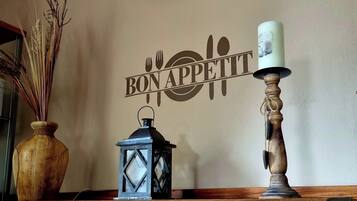 Um relógio de parede, um castiçal e uma placa decorativa com a inscrição 'BON APPETIT'.