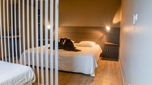 Quarto com duas camas, piso de madeira e divisória branca.