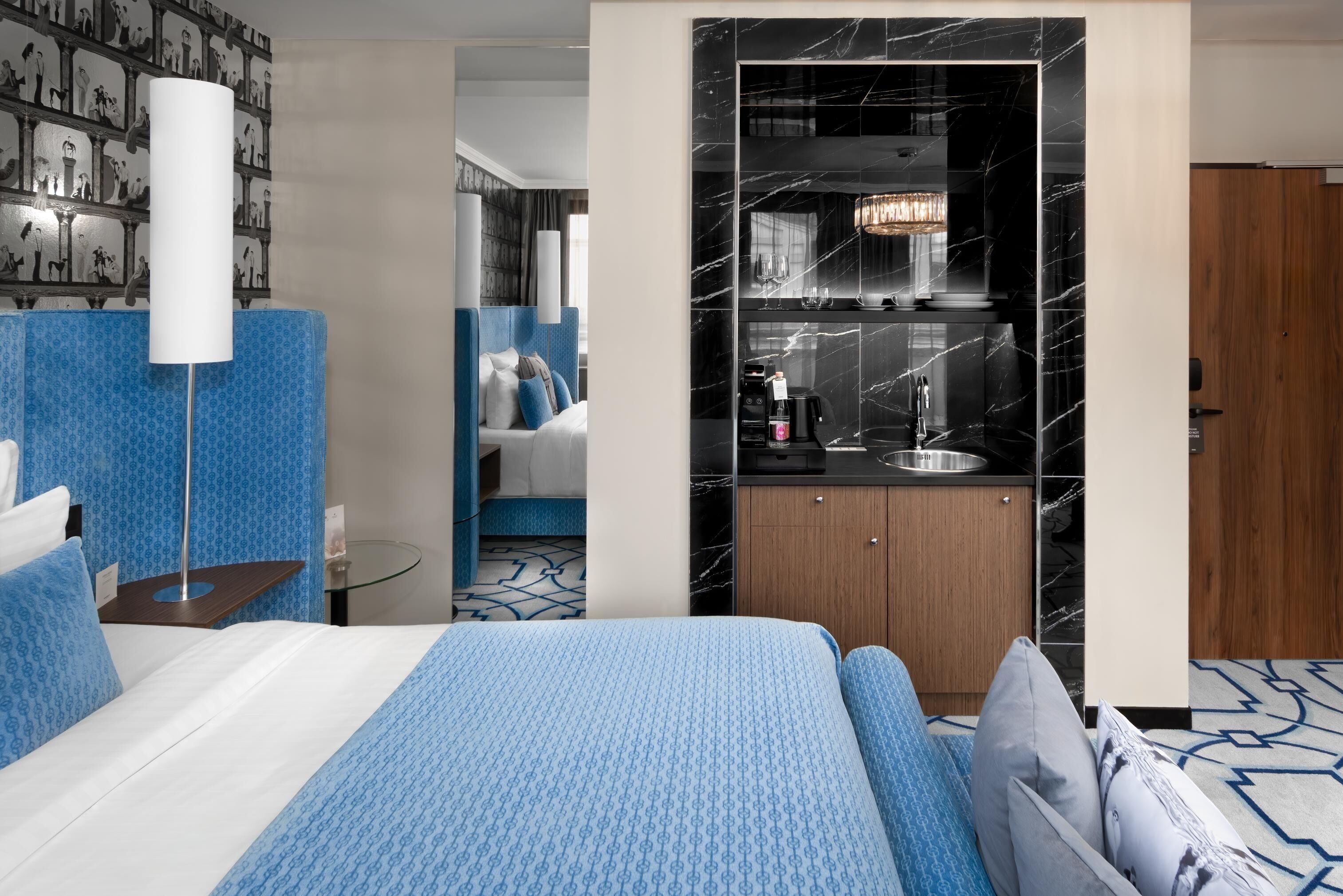 Quarto de hotel com cama, uma kitchenette compacta, banheiro e área de estar.