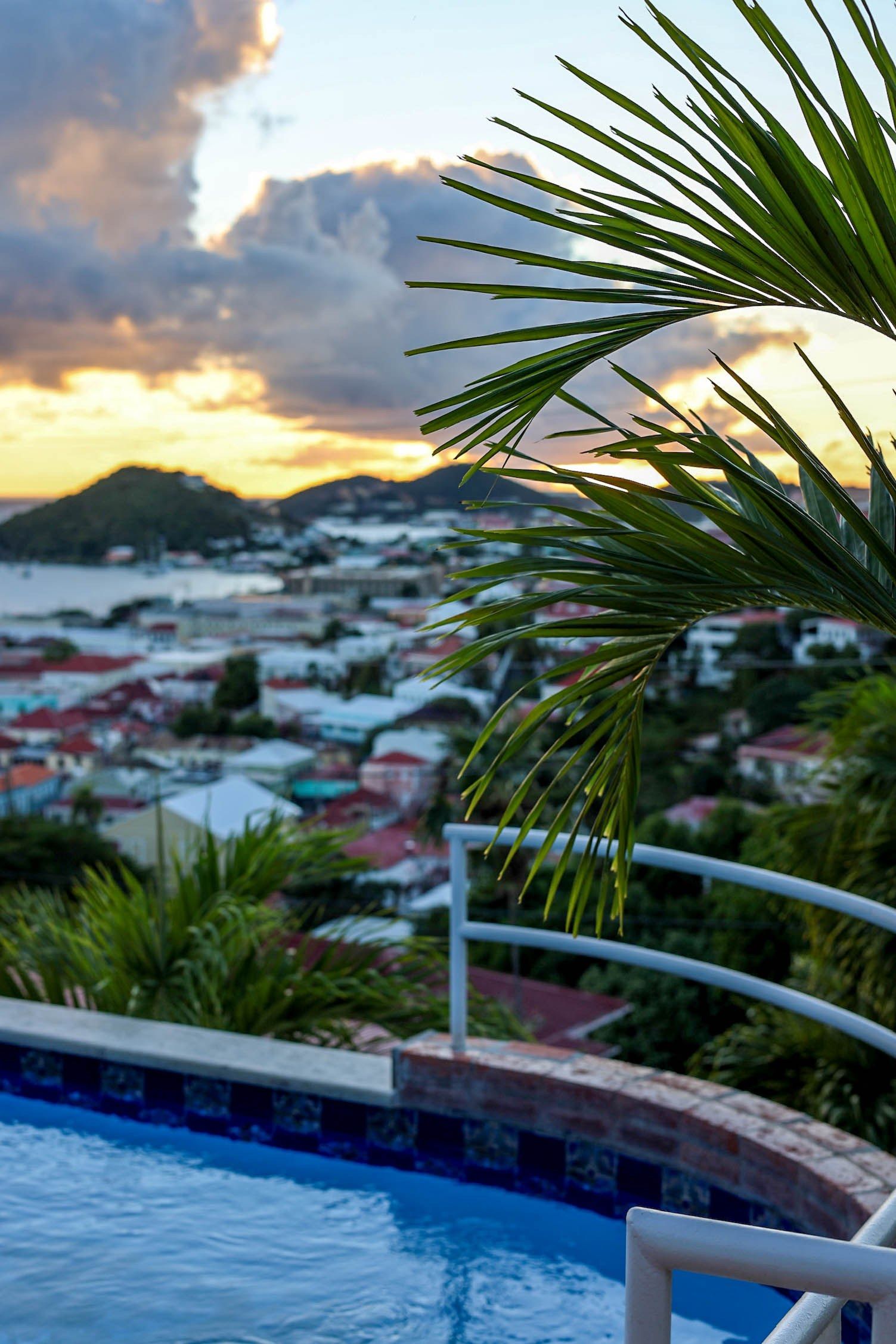 Piscina com vista para uma cidade costeira ao pôr do sol.
