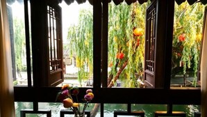Quarto em estilo tradicional chinês com vista para um jardim aquático e lanternas penduradas.