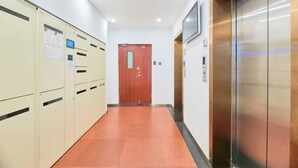 Um corredor com carpete vermelho, porta de madeira e elevador.