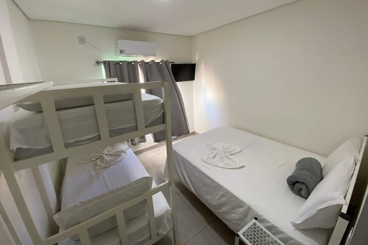 Quarto com beliche, uma mesa pequena e um ventilador de teto.