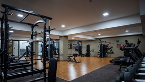 Uma academia com diversos equipamentos de exercício, incluindo aparelhos de musculação e pesos livres.