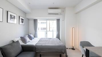 Um quarto moderno com cama, sofá, mesa e abajur.
