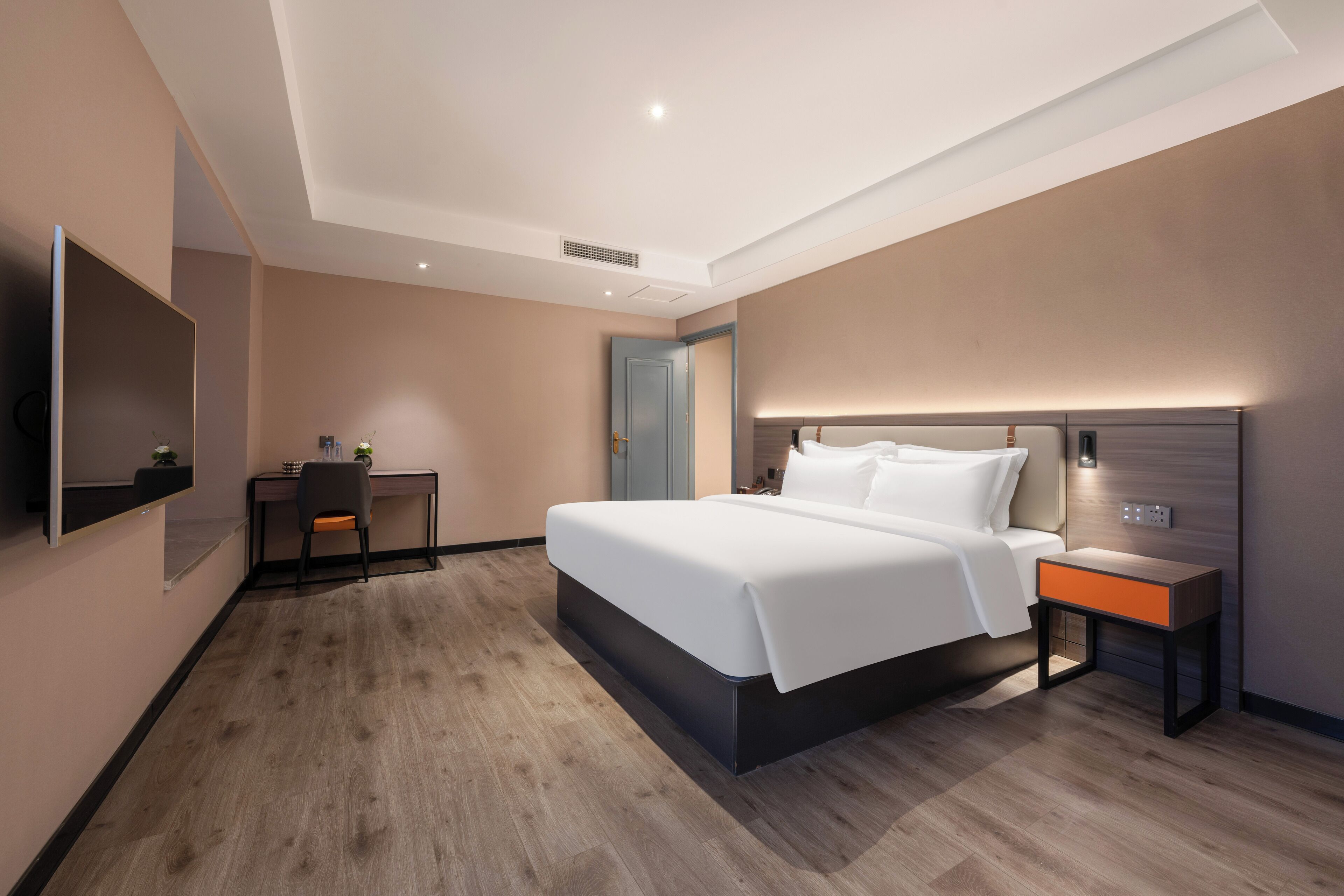 Quarto de hotel moderno com uma cama grande, uma escrivaninha e uma televisão.