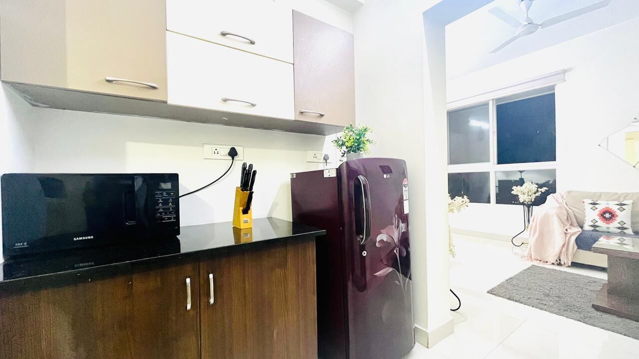 Cozinha moderna com micro-ondas, frigorífico e armários de madeira.