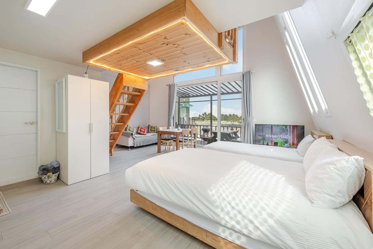 Quarto moderno com uma cama grande, escada de madeira e varanda com vista.