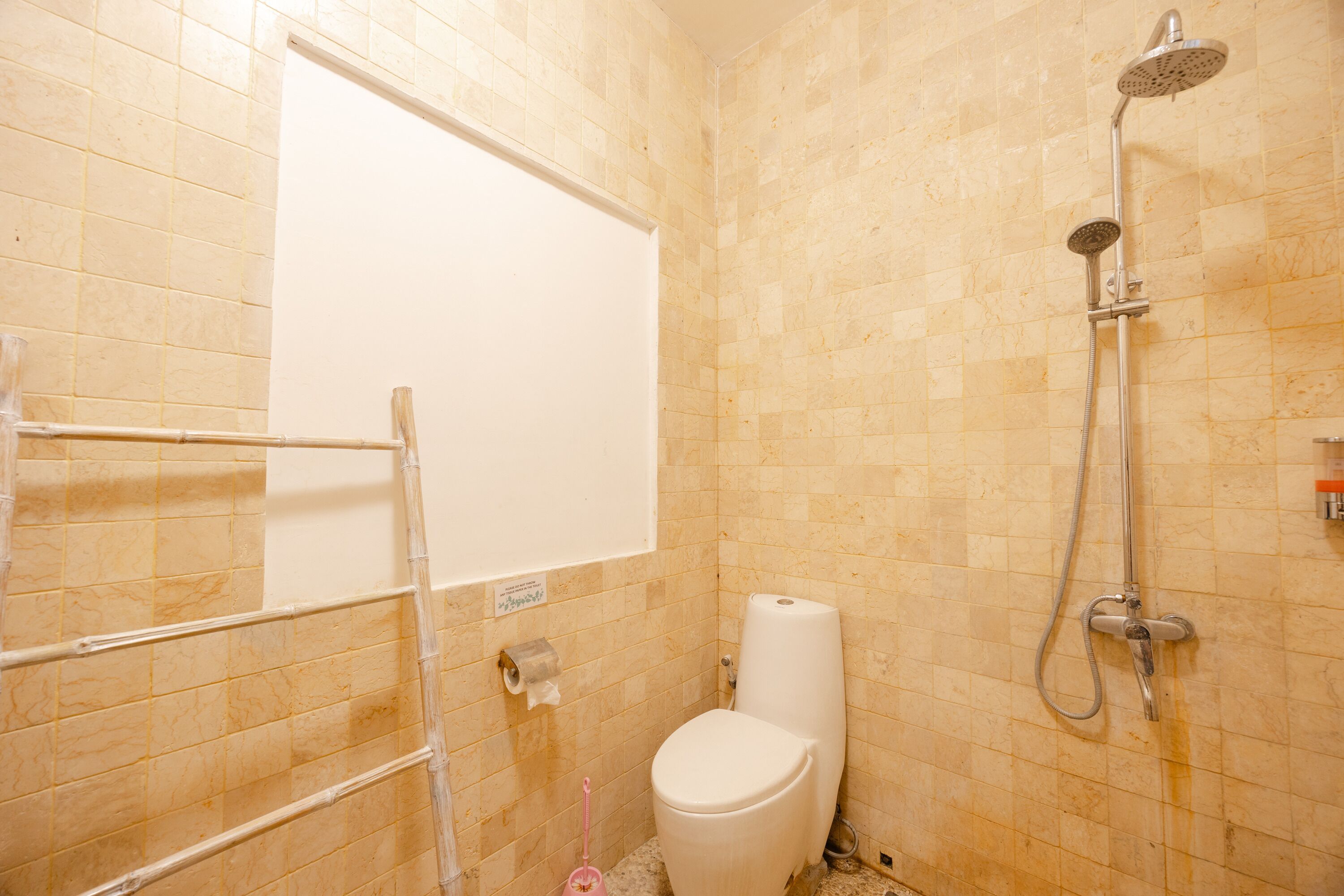 Uma casa de banho com sanita, chuveiro e porta-toalhas.