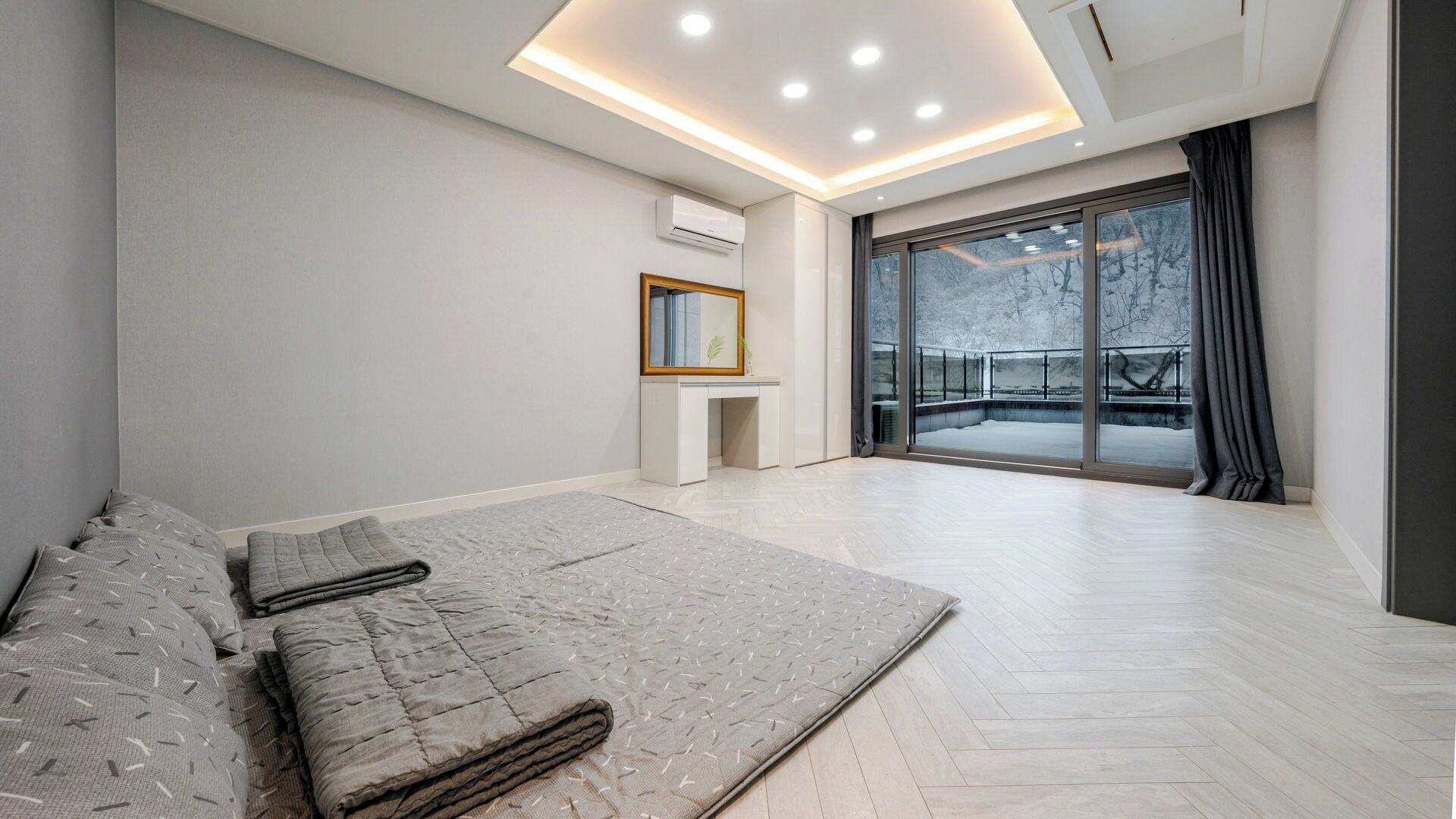 Quarto moderno com uma cama grande, uma escrivaninha e vista para uma paisagem nevada pela janela.