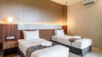 Quarto de hotel com duas camas, uma mesa de cabeceira de madeira, um painel de cabeceira de mármore e um aparelho de ar condicionado.