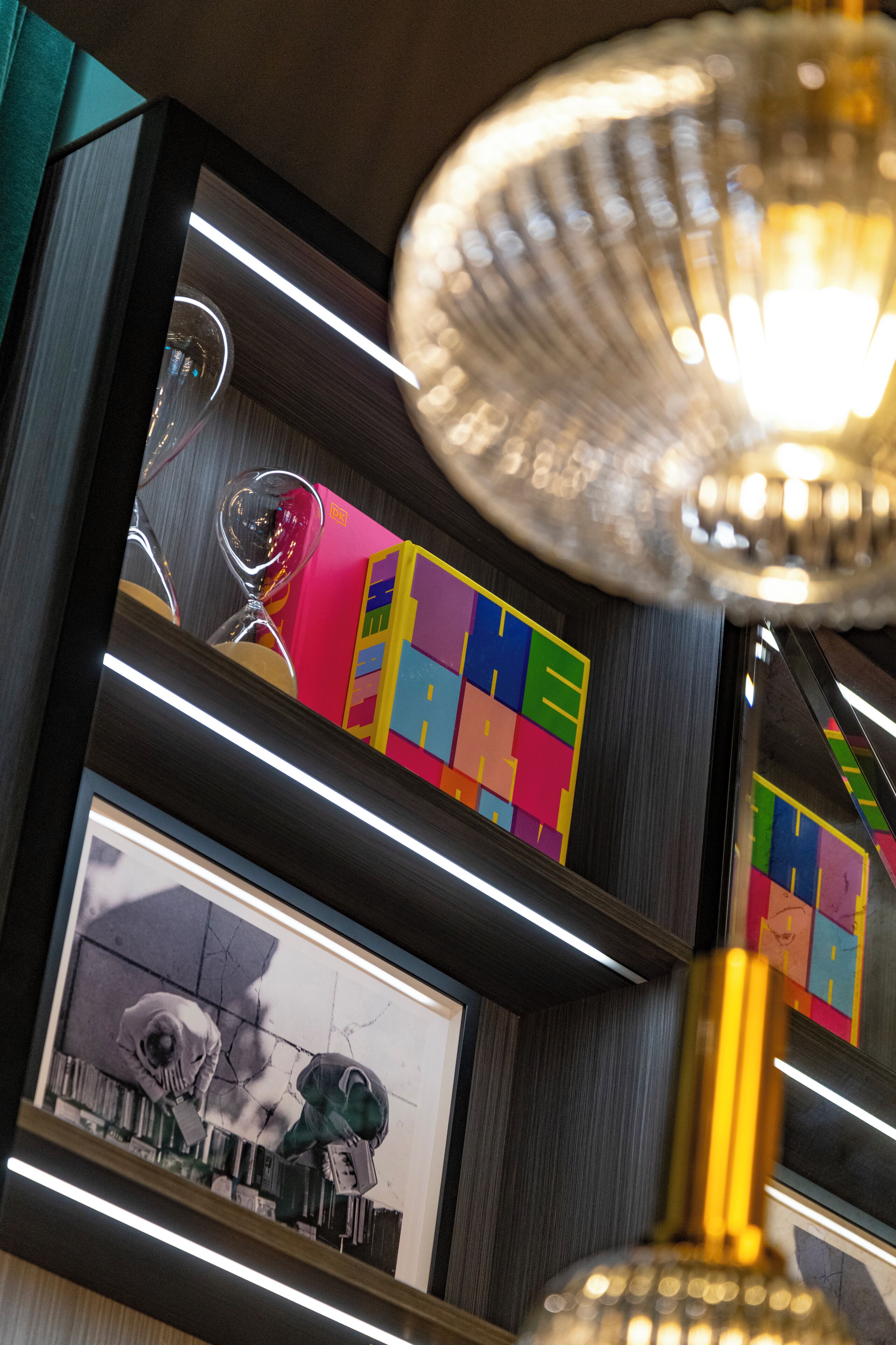 Um interior moderno com painéis de madeira, uma obra de arte colorida e uma luminária de teto refletora.