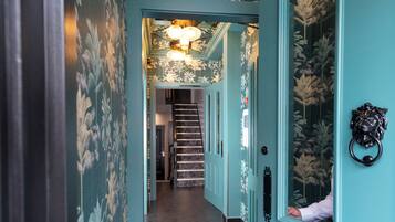 Um corredor com escada, paredes verde-água e papel de parede com padrão floral.