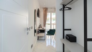 Quarto de hotel moderno com uma janela grande, uma escrivaninha com cadeira e um cabideiro.