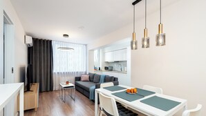 Uma sala de estar moderna com área de jantar, um sofá e uma cozinha ao fundo.