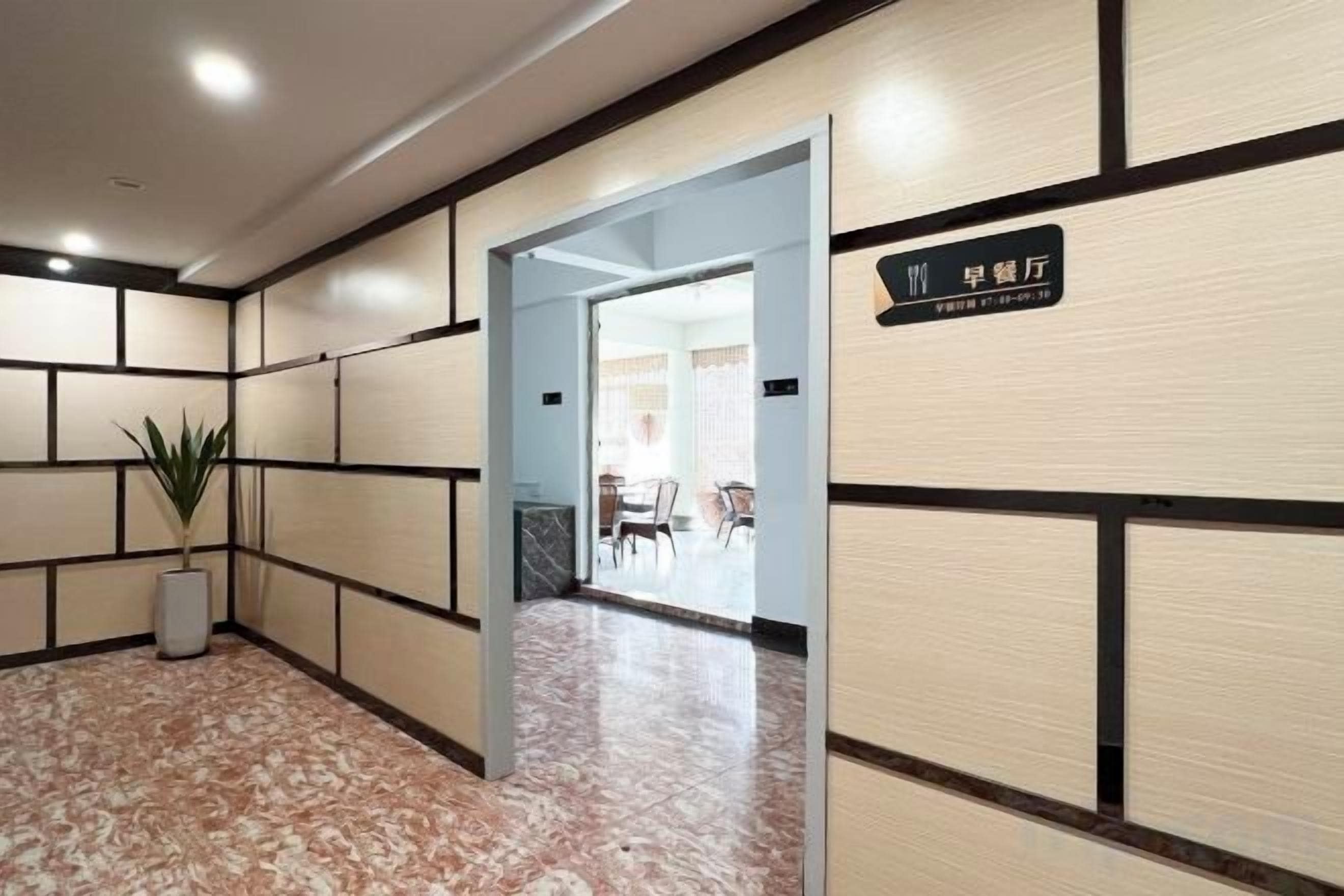 Uma área de recepção com piso de azulejos, um vaso de planta e uma placa indicando a localização.