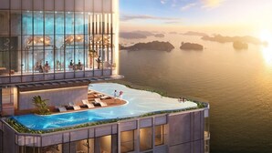 Um hotel moderno com piscina infinita no terraço e vista para a água.