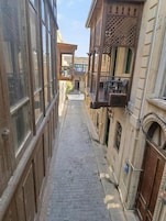 Um estreito beco de paralelepípedos entre edifícios com varandas de madeira e janelas grandes.