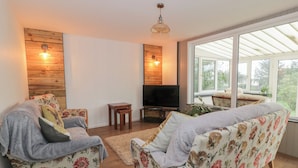 Uma sala de estar acolhedora com sofá, poltrona, televisão e painéis de parede em madeira.