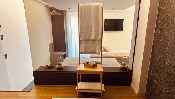 Quarto moderno com cama grande, abajures, mesa de cabeceira de madeira e uma banheira espaçosa.