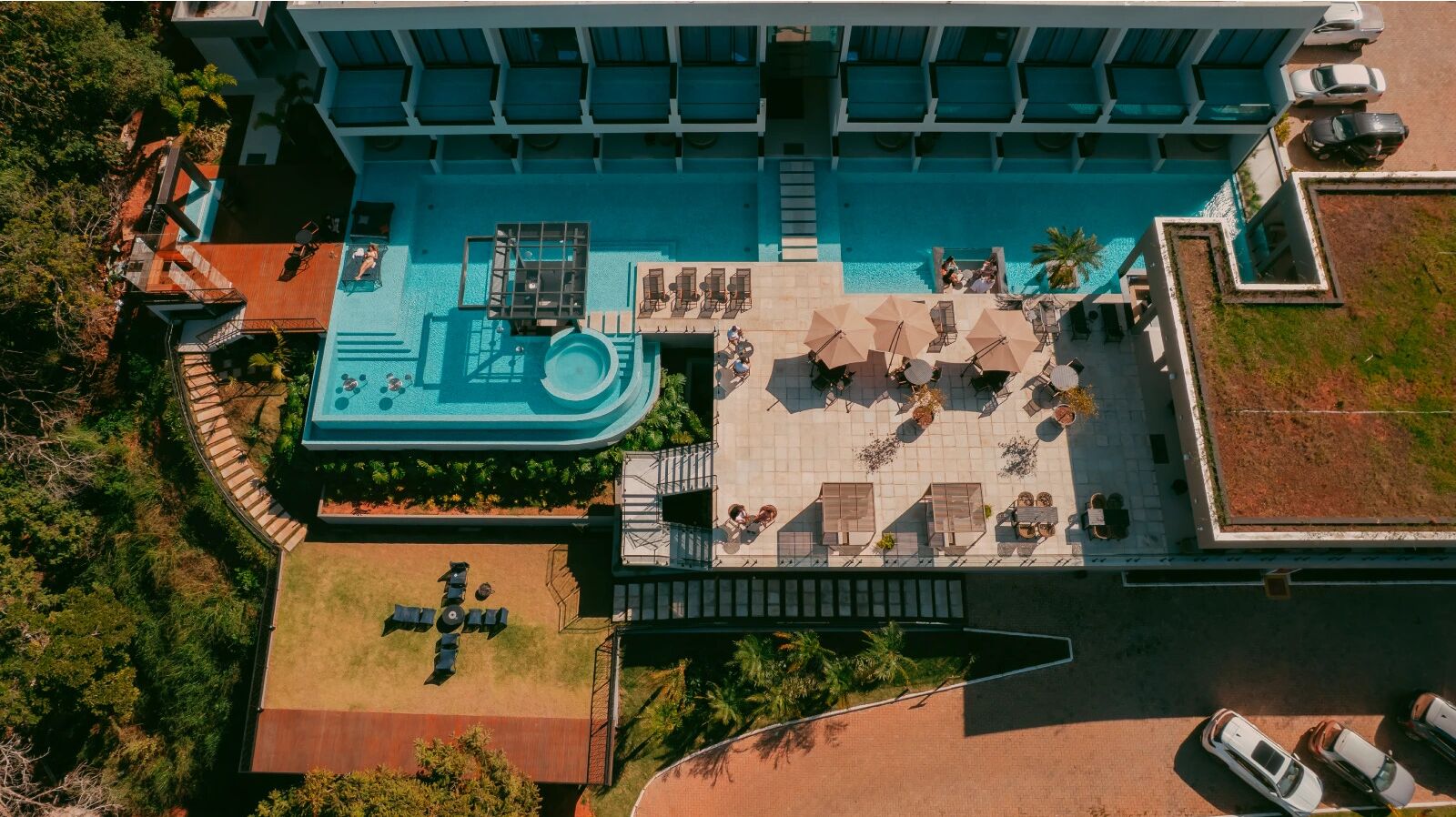 Vista aérea de um hotel com piscina, área de estar externa e um alpendre coberto.