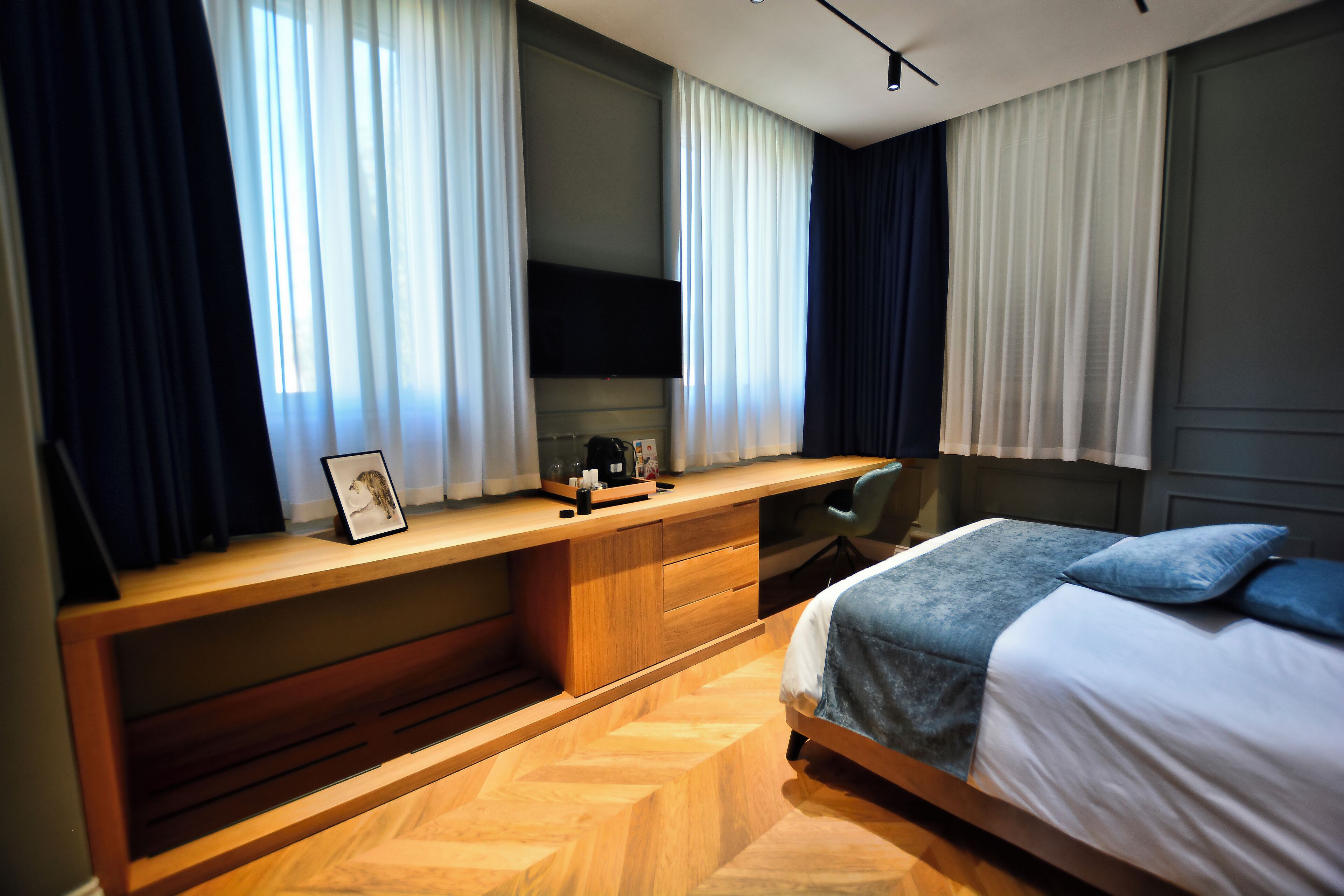 Um quarto moderno com uma escrivaninha de madeira, uma cama e uma TV fixada na parede.