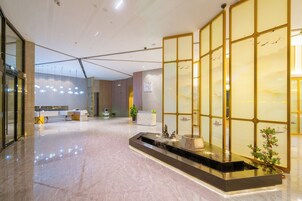 Um lobby moderno com balcão de recepção, área de estar e uma fonte decorativa.