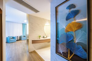 Um saguão de hotel moderno com área de estar, balcão de recepção e uma obra de arte emoldurada na parede.