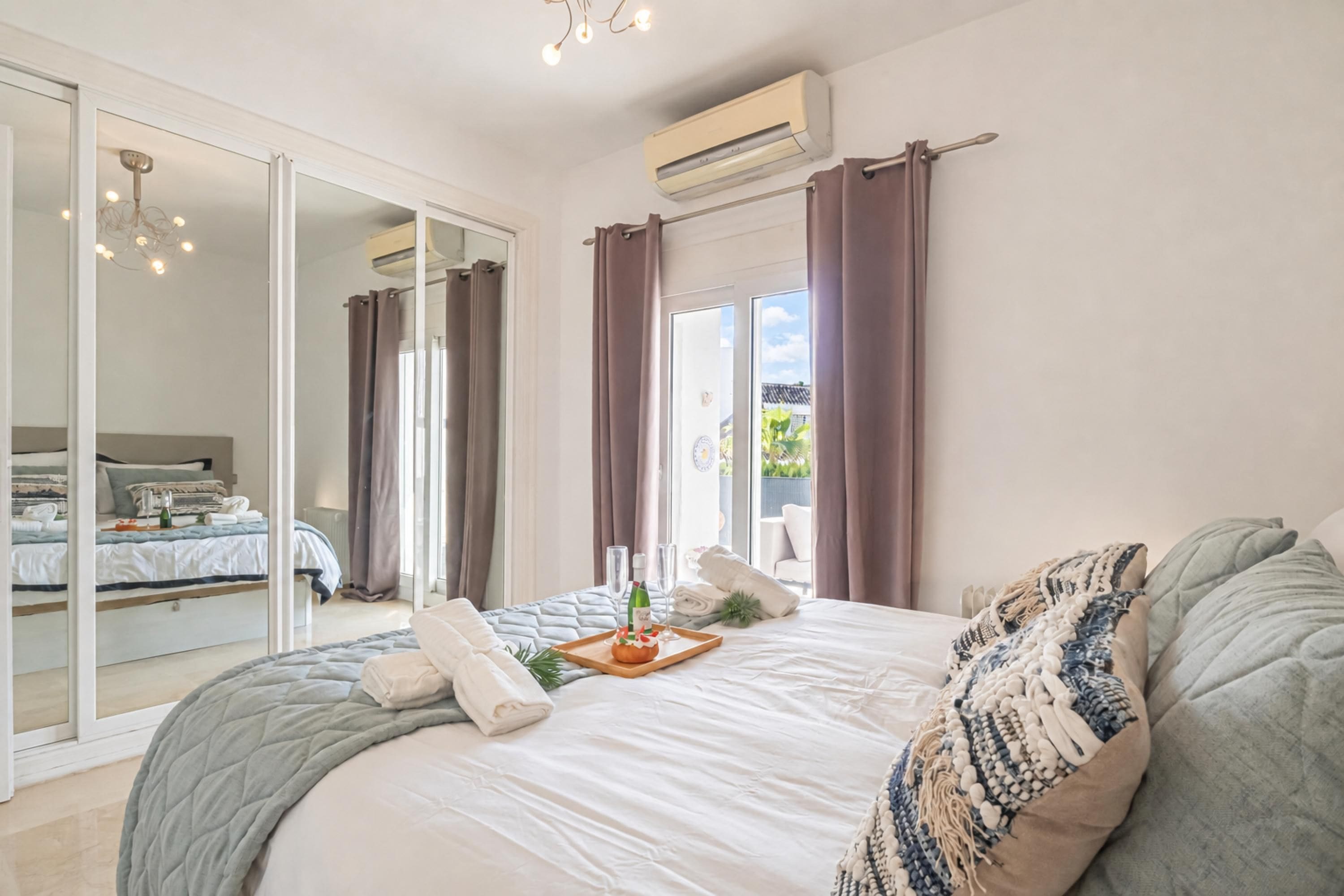 Um quarto espaçoso com uma cama grande, uma porta de vidro deslizante para uma varanda e um ar condicionado na parede.