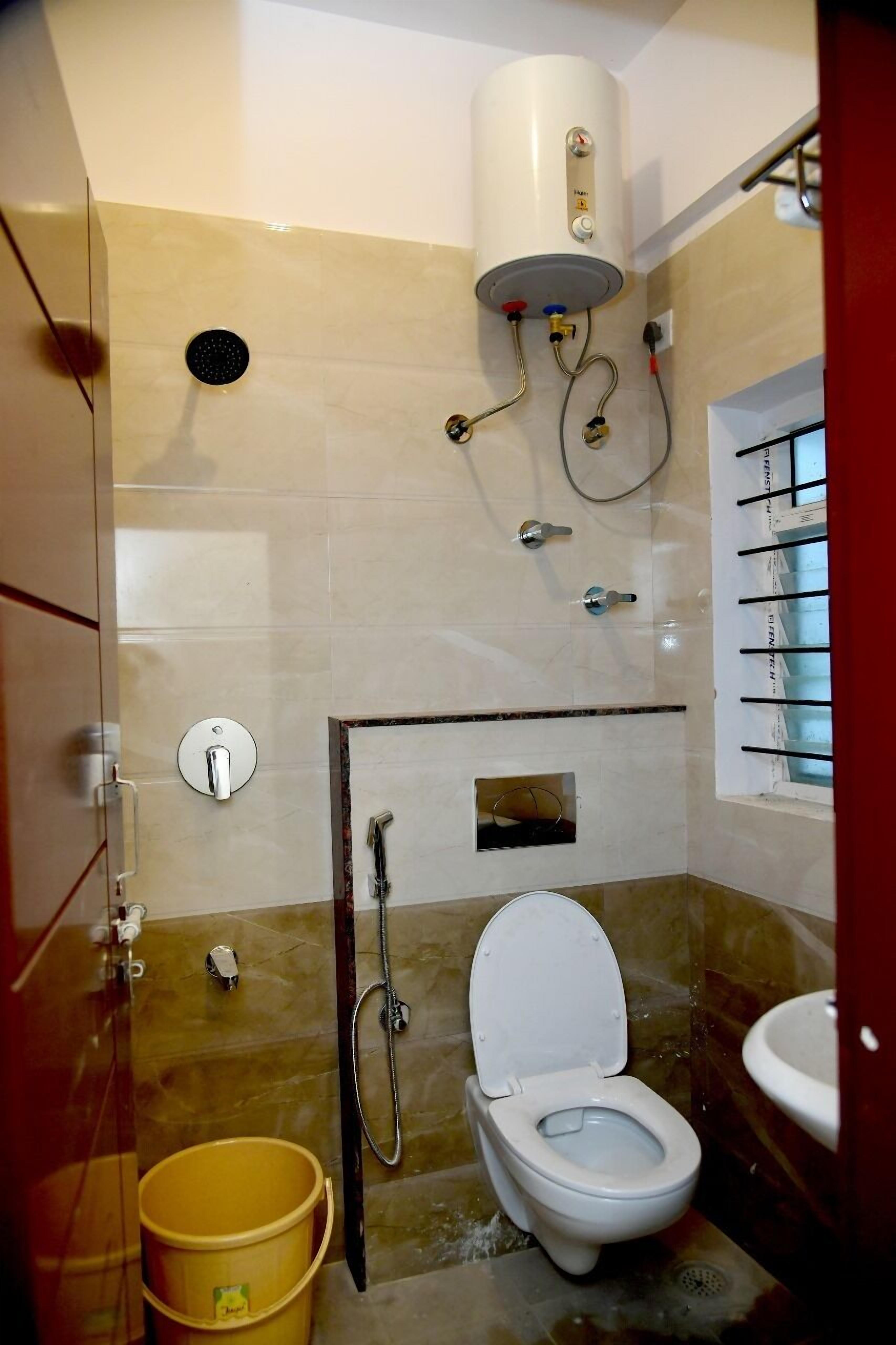 Casa de banho com sanita, chuveiro e lavatório.