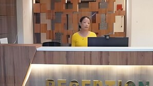 Uma mesa de recepção com design em painel de madeira e a palavra "RECEPTION" em destaque.