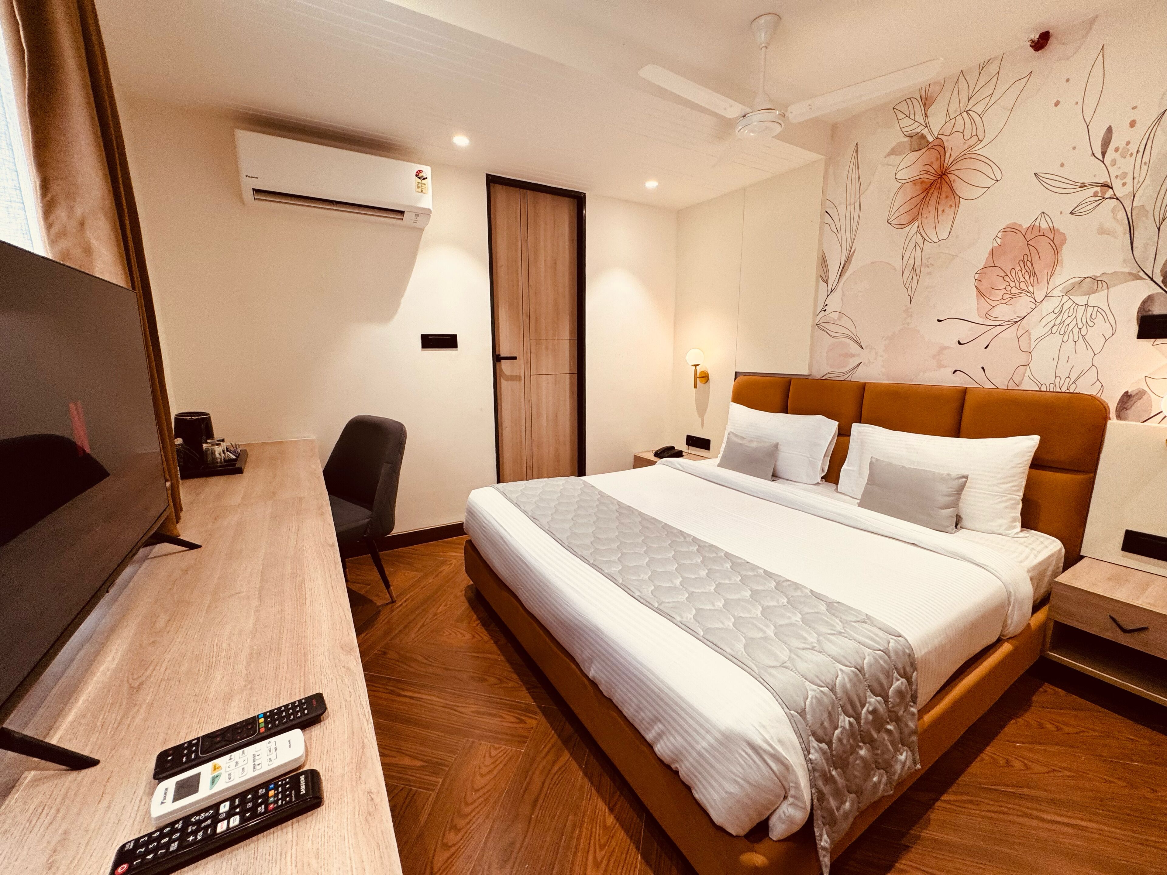 Quarto de hotel com uma cama, uma escrivaninha, uma televisão e uma cadeira.