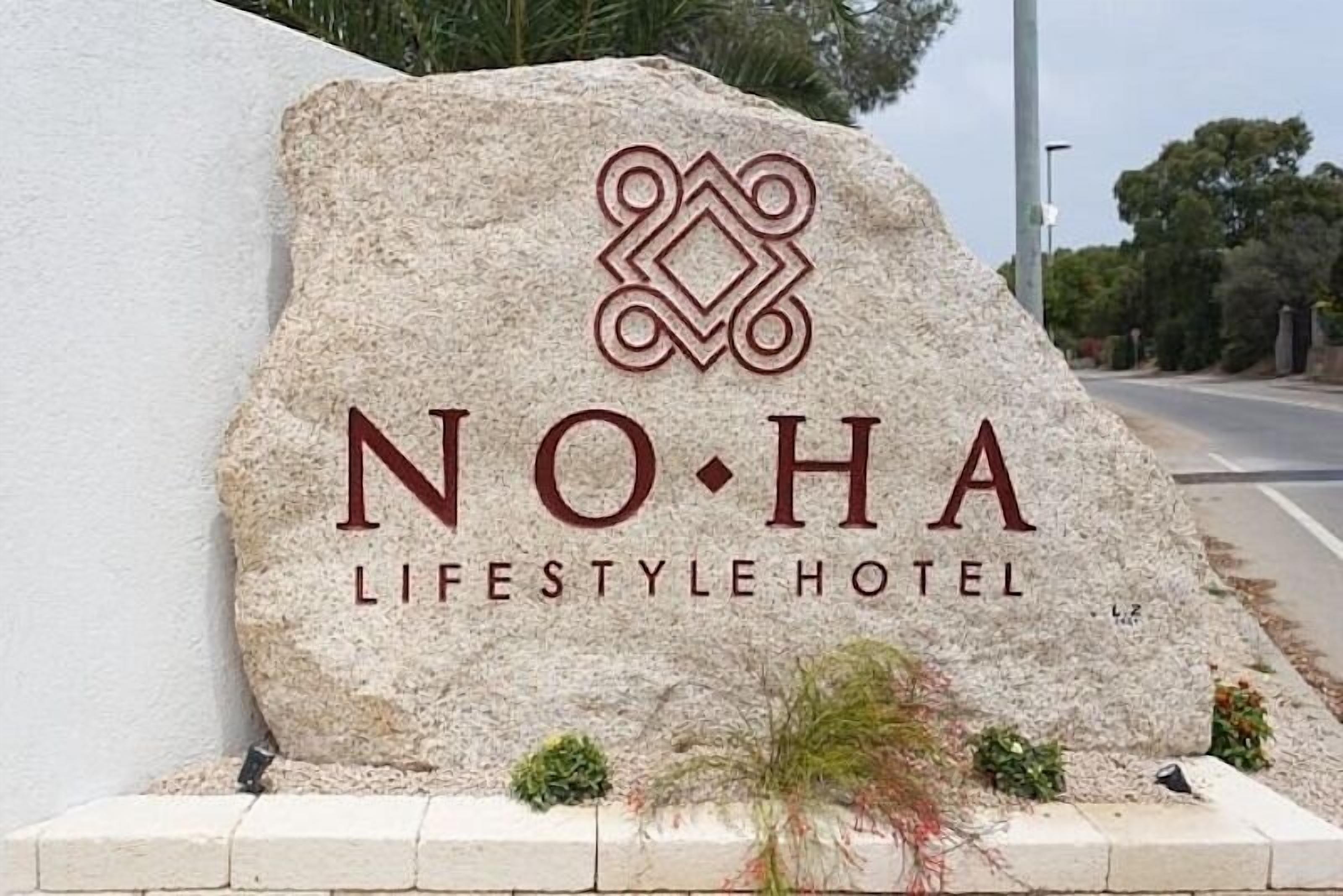 Uma grande placa de pedra com o texto "NOHA LIFESTYLE HOTEL" e um logotipo decorativo.