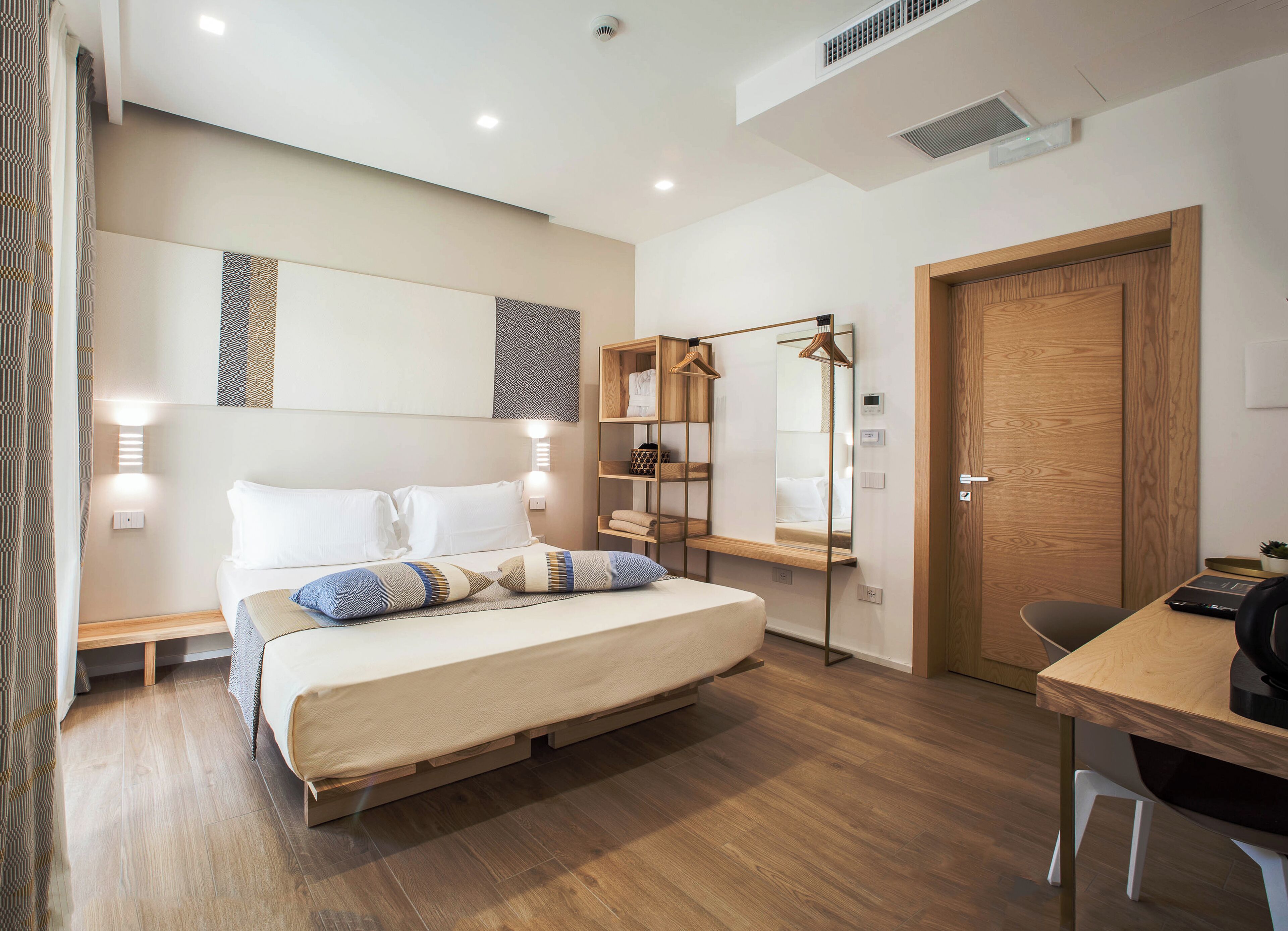 Quarto moderno com cama, mesas de cabeceira, escrivaninha e guarda-roupa.