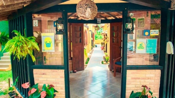 Entrada de hotel com um caminho de azulejos que leva a uma porta de madeira.
