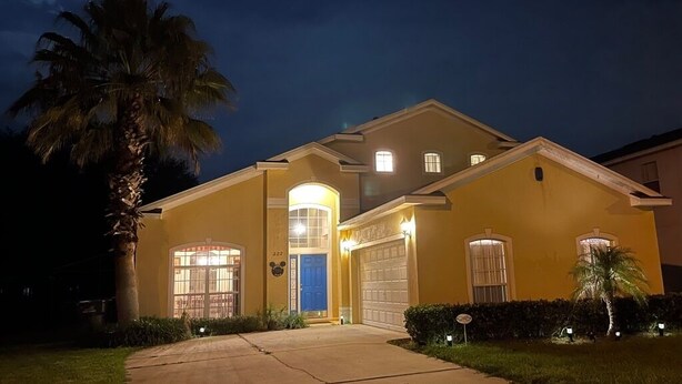 Uma casa de dois andares com garagem, varanda frontal e entrada bem iluminada.