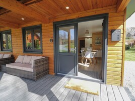 Uma cabana de madeira com varanda coberta, área de jantar e porta de correr de vidro que dá para o interior.